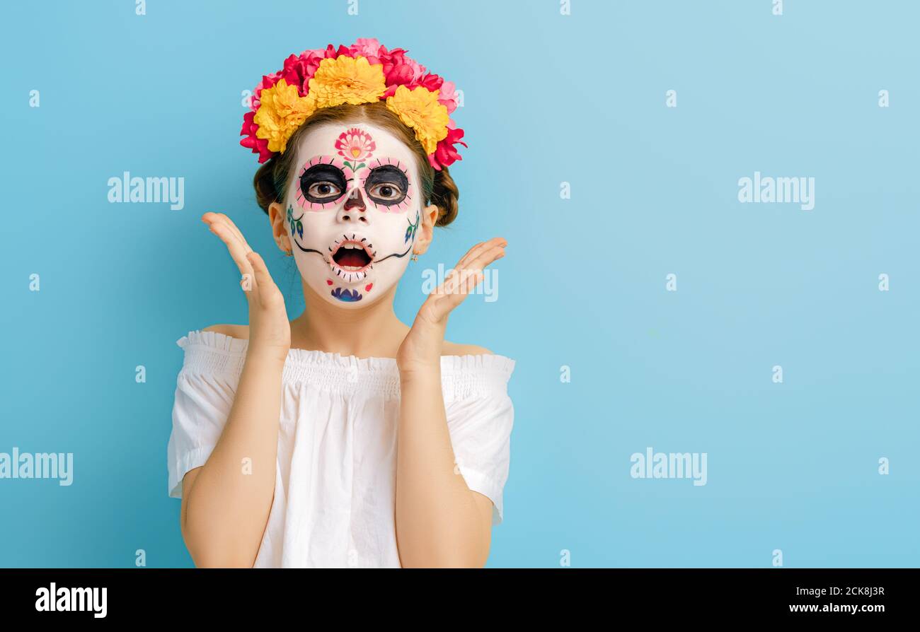 Adorable zombie in flower wreath posing on blue background. Happy child ...