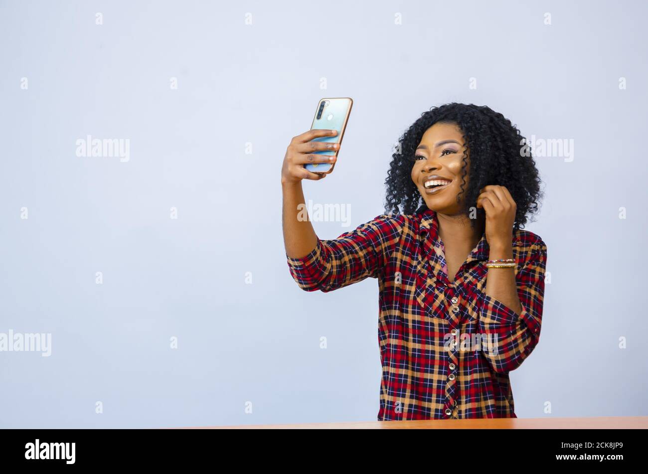 African cheerful female holding a cellphone with an excited face ...