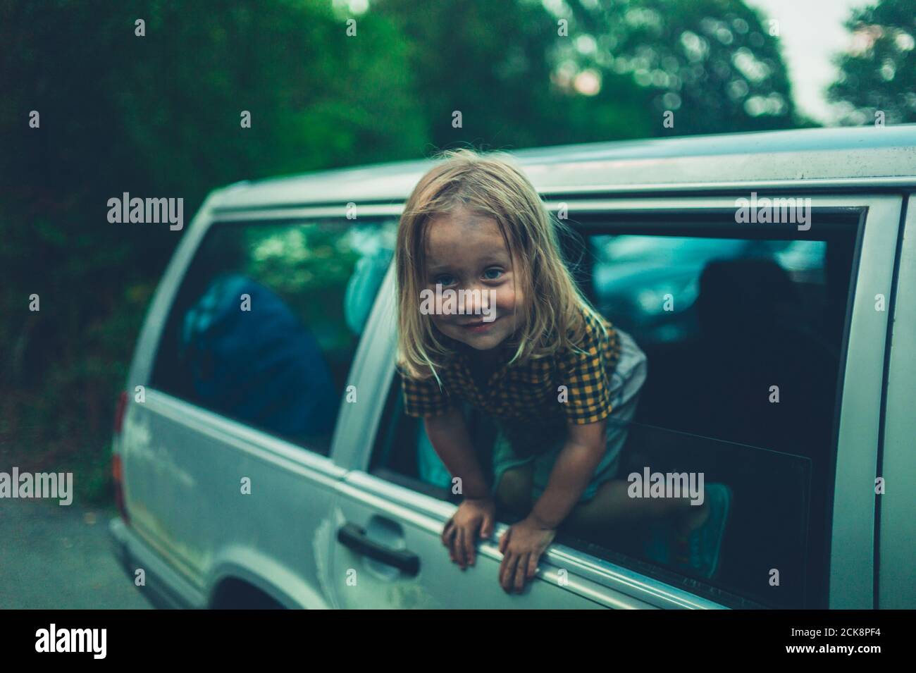 A little preschooler is hanging out the window of a parked car Stock ...
