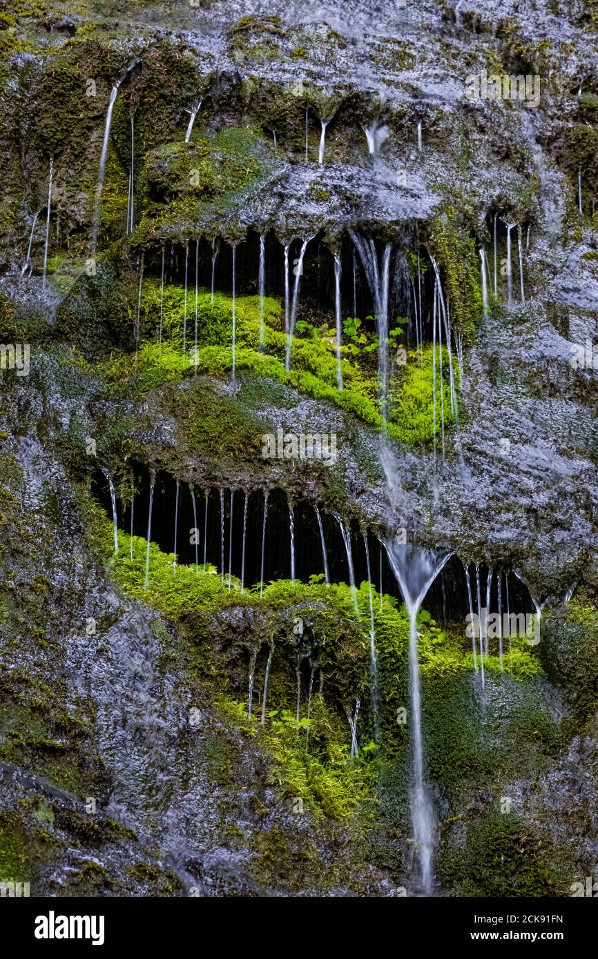 Patterns of water dripping down the face of a waterfall in a grotto ...