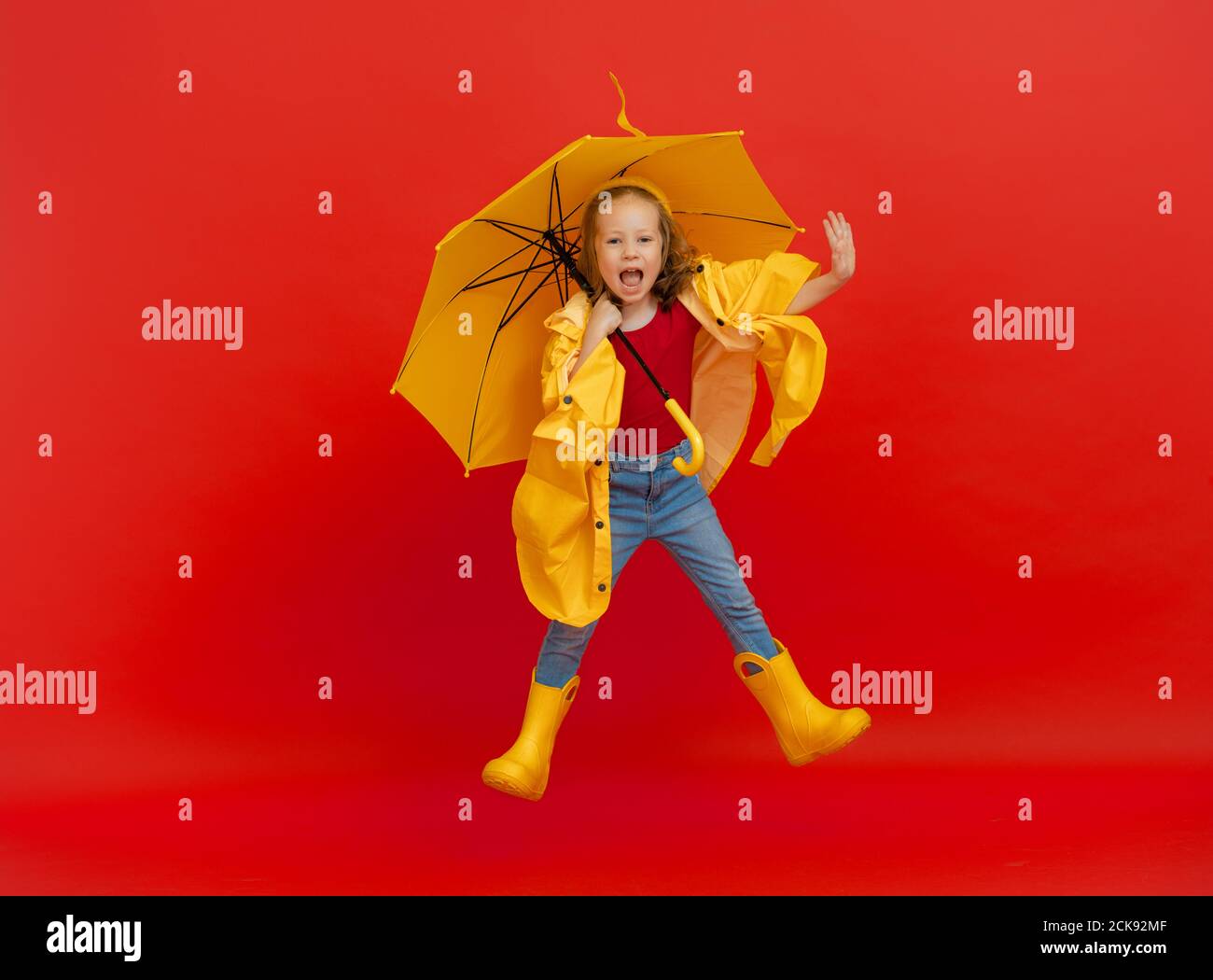 Happy emotional child laughing and jumping. Kid with yellow umbrella on ...