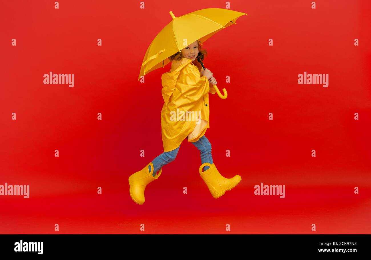 Happy emotional child laughing and jumping. Kid with yellow umbrella on ...