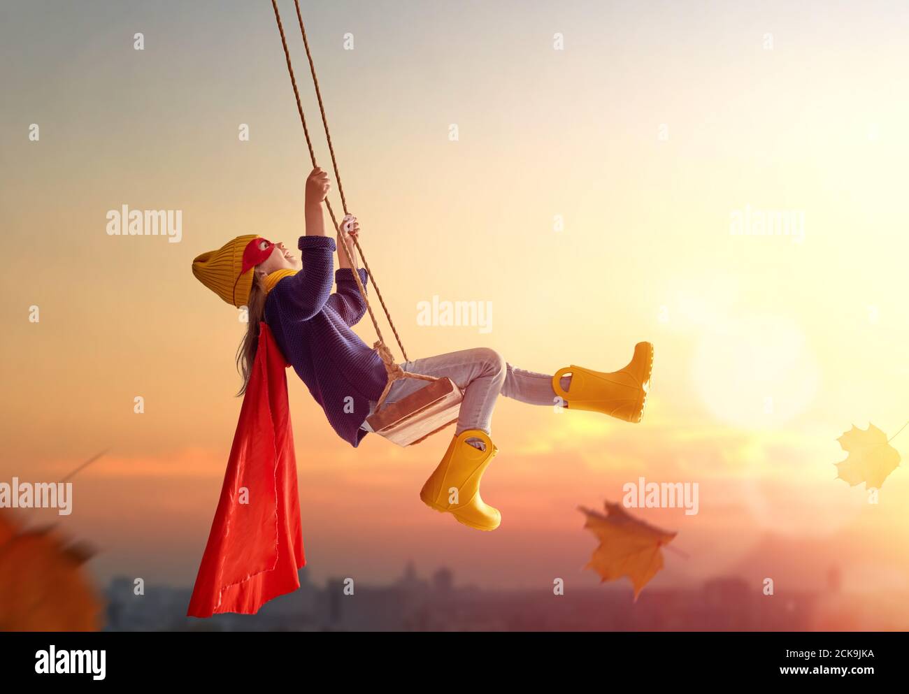 Happy child on swing in sunset fall. Little kid playing in the autumn ...
