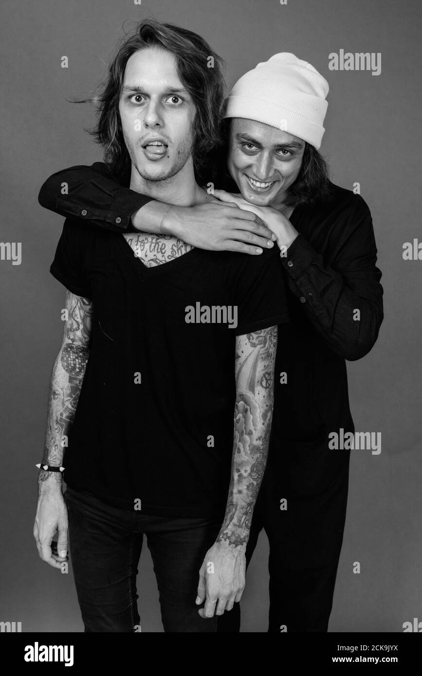 Two young handsome men together against gray background Stock Photo - Alamy