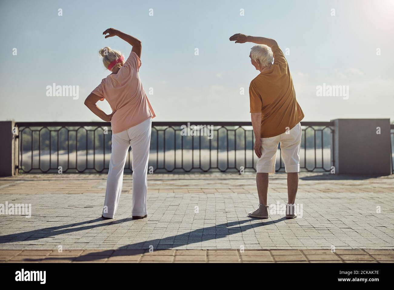 Two people doing a side bend exercise outdoors Stock Photo - Alamy