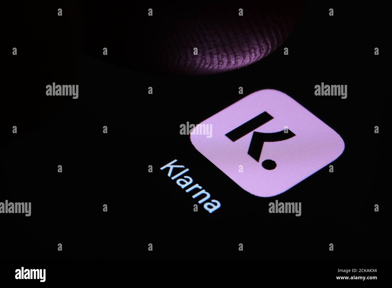 Klarna app logo seen on the screen and blurred finger tip above it ...