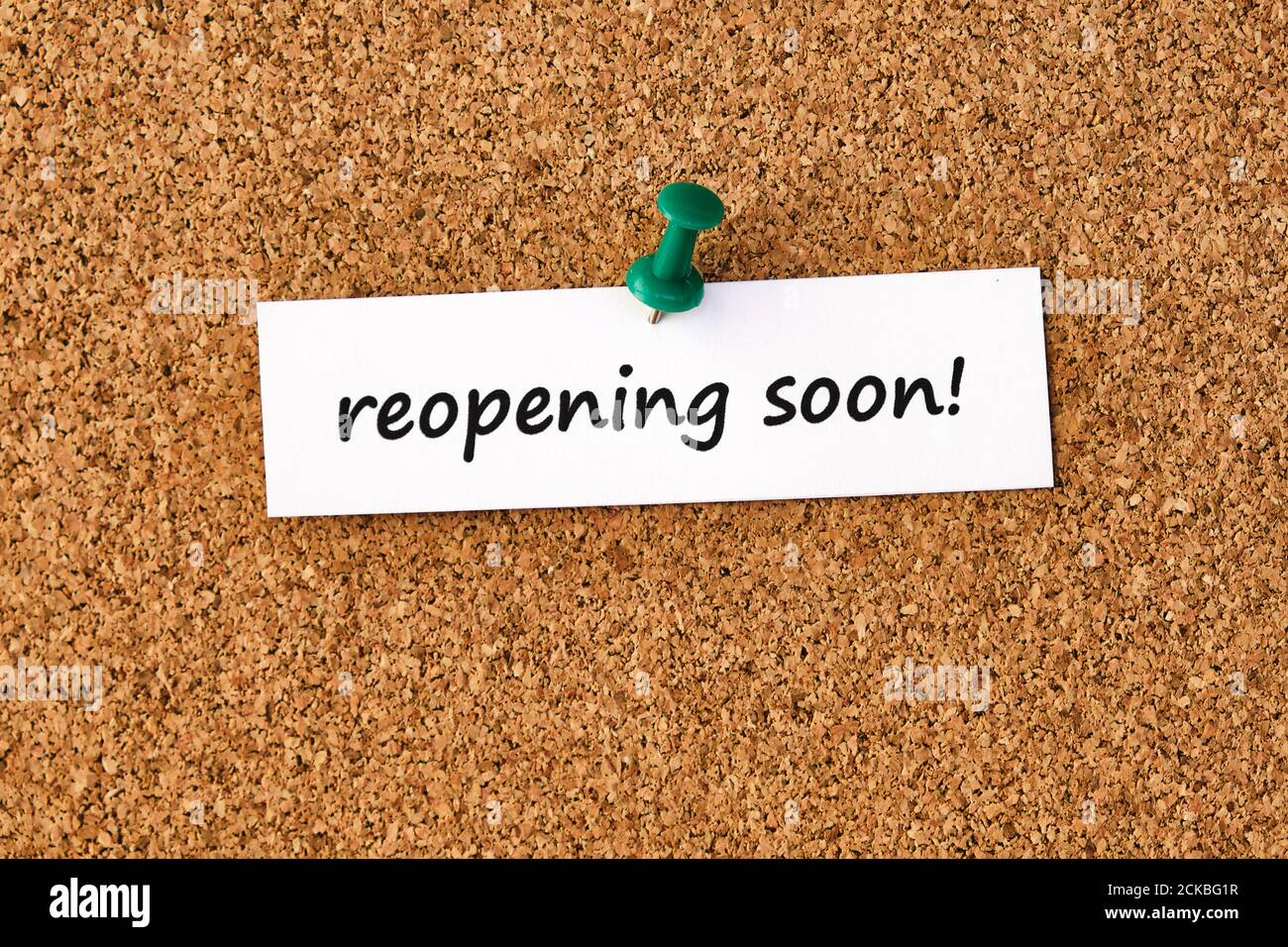 Reopening soon. Text written on a piece of paper or note, cork board ...