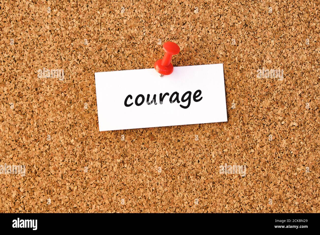 Courage. Word written on a piece of paper or note, cork board ...