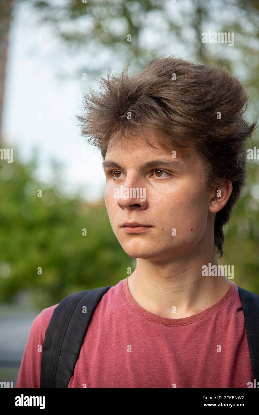 Portrait of a young teenager 17 years old in a red t-shirt with thick ...