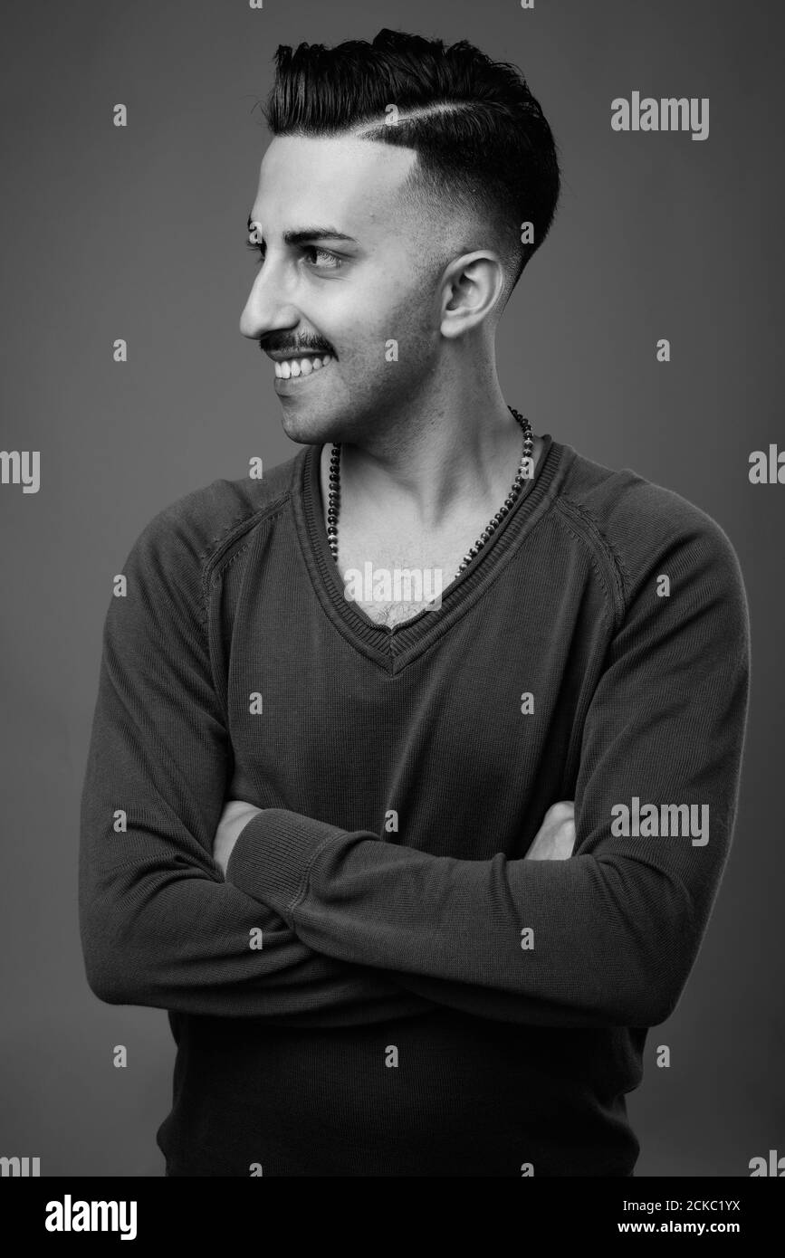 Young handsome Iranian man with mustache against gray background Stock ...