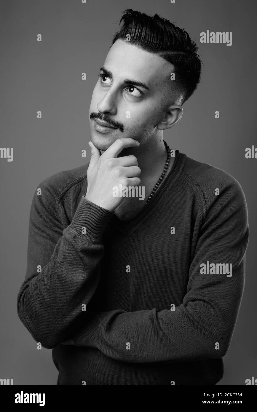 Young handsome Iranian man with mustache against gray background Stock ...