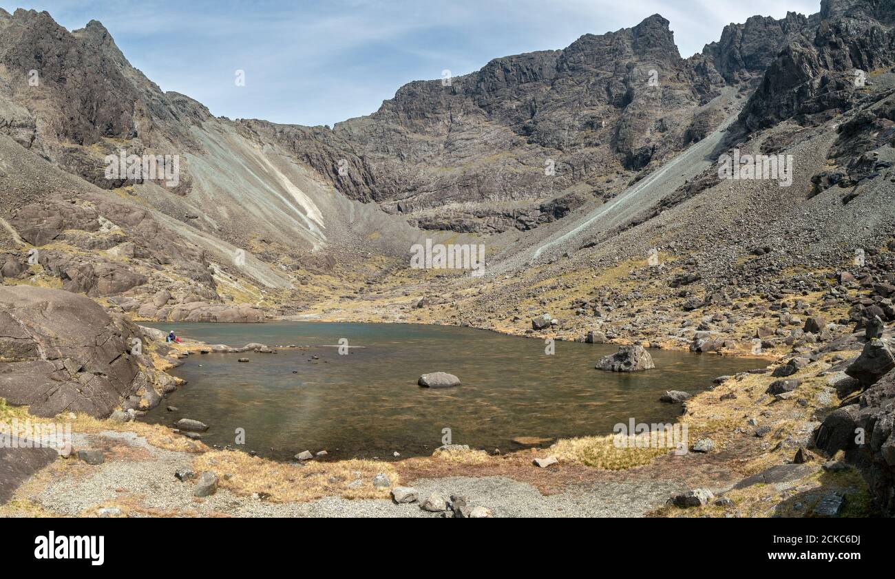 Lone female walker sits beside waters of Coire Lagan below the Cuillin ...