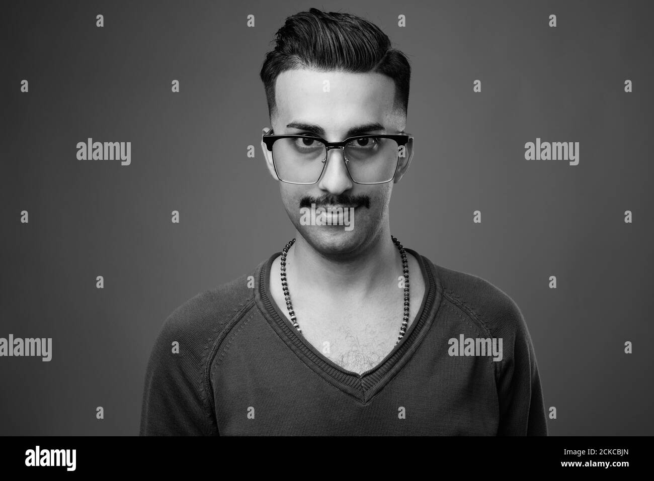 Young handsome Iranian man with mustache against gray background Stock ...