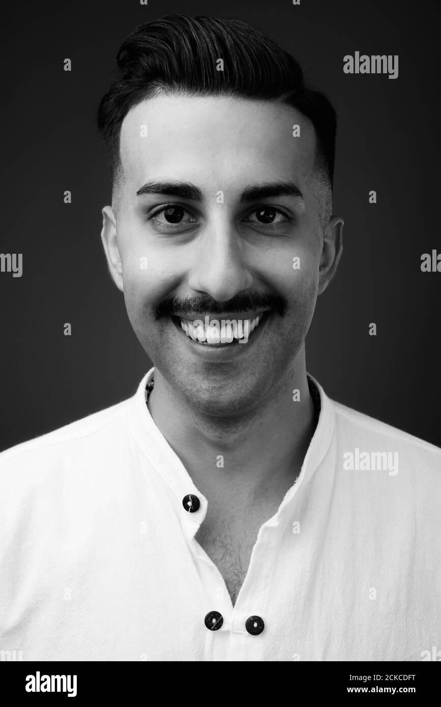 Young handsome Iranian man with mustache against gray background Stock ...