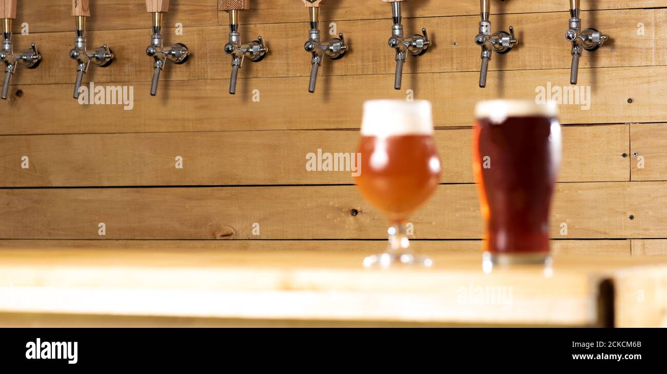 Draft beer freshly served on the yellow illuminated wooden counter ...