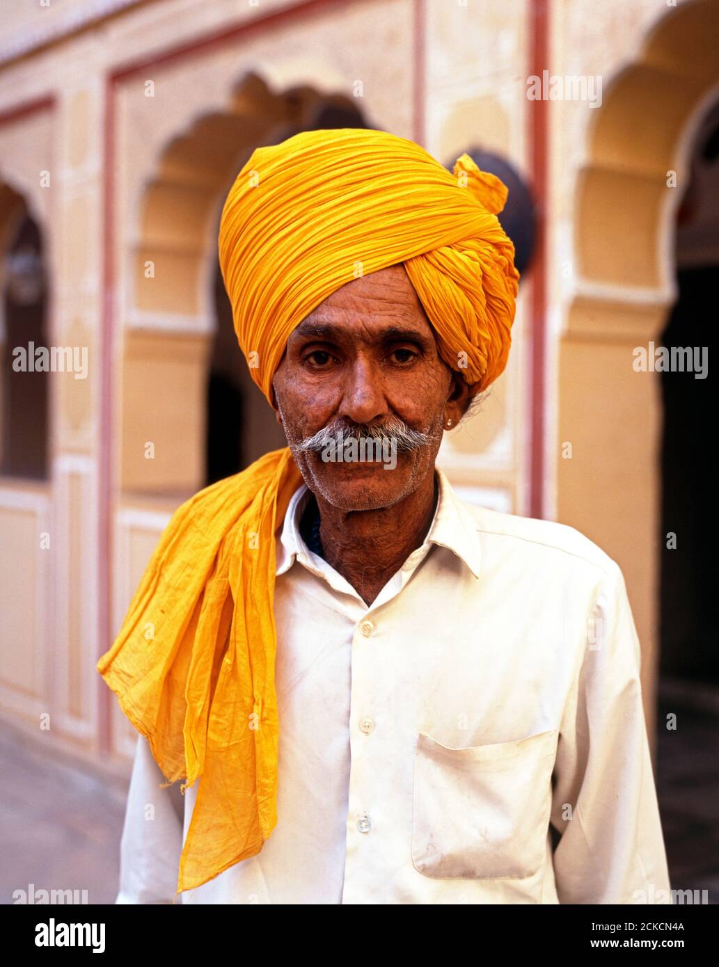 Indian man wearing a yellow turban standing outside the Samode Palace ...