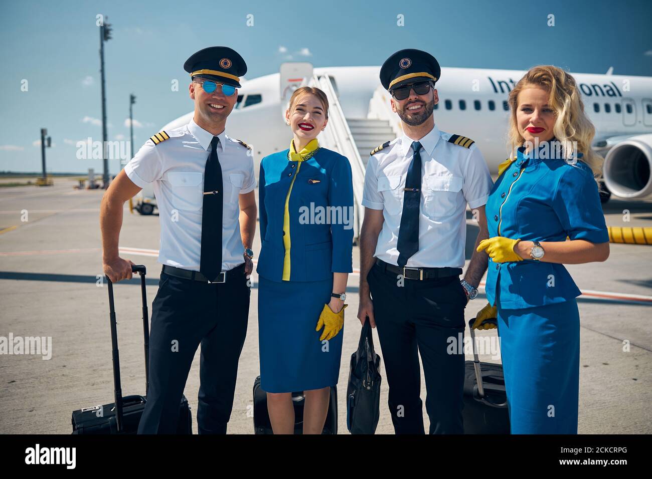 Handsome male pilots and beautiful female stewardesses looking at ...