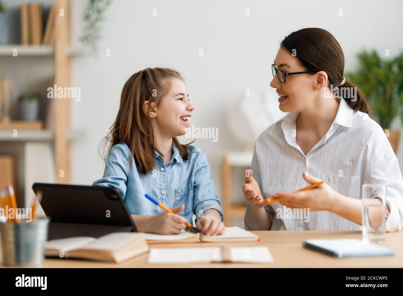 Back to school. Happy child and adult are sitting at desk. Girl doing ...