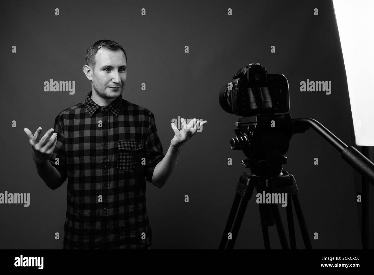 Portrait of hipster man vlogging with camera against gray background ...