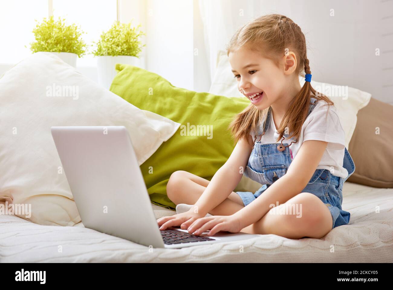 Child little girl with a laptop computer at home. Happy little child ...
