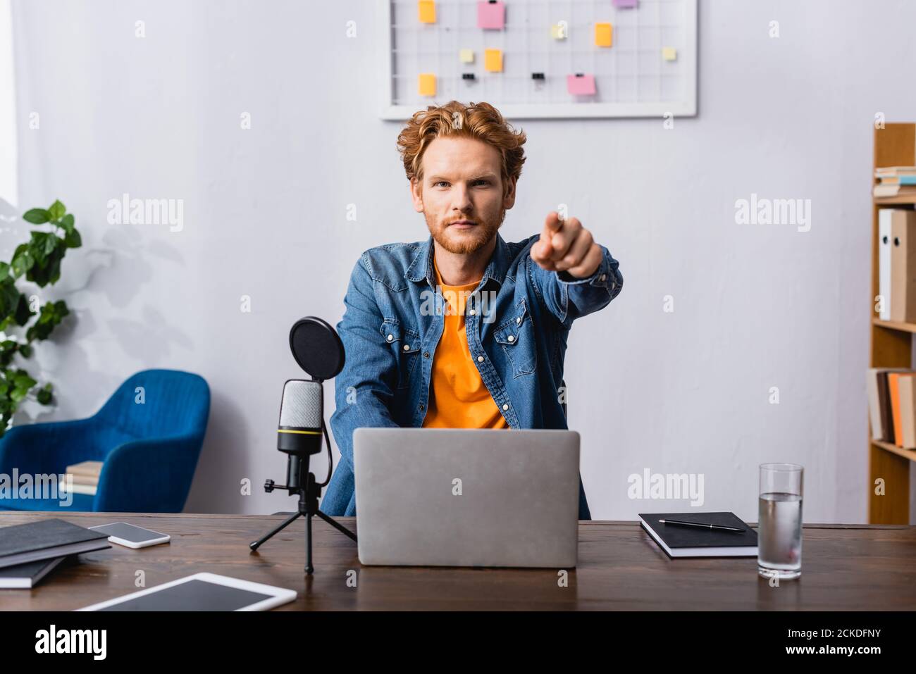 serious radio host in denim shirt pointing with finger at camera while ...