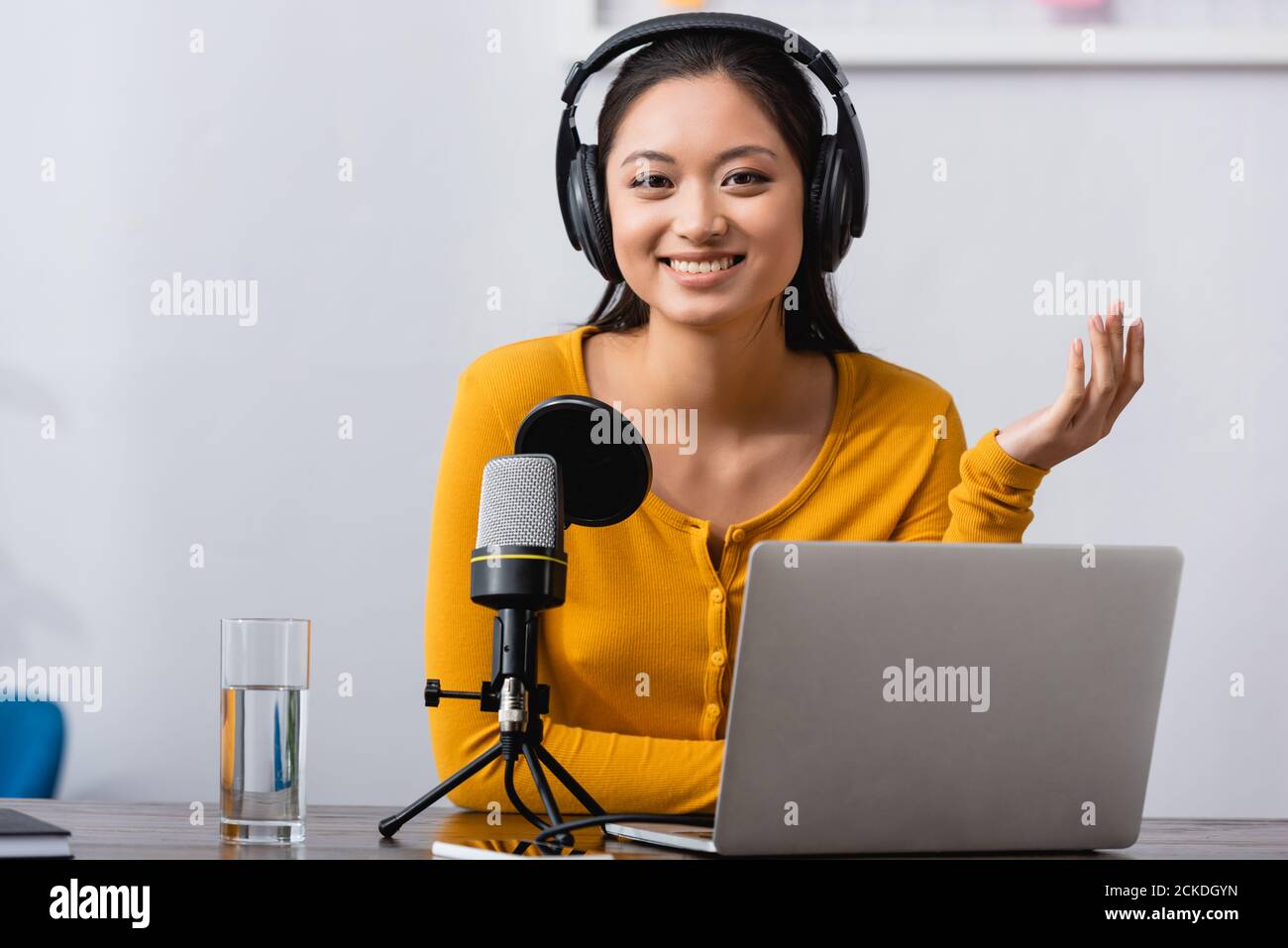 Sitting smiling gesturing microphone communication looking at camera hi ...