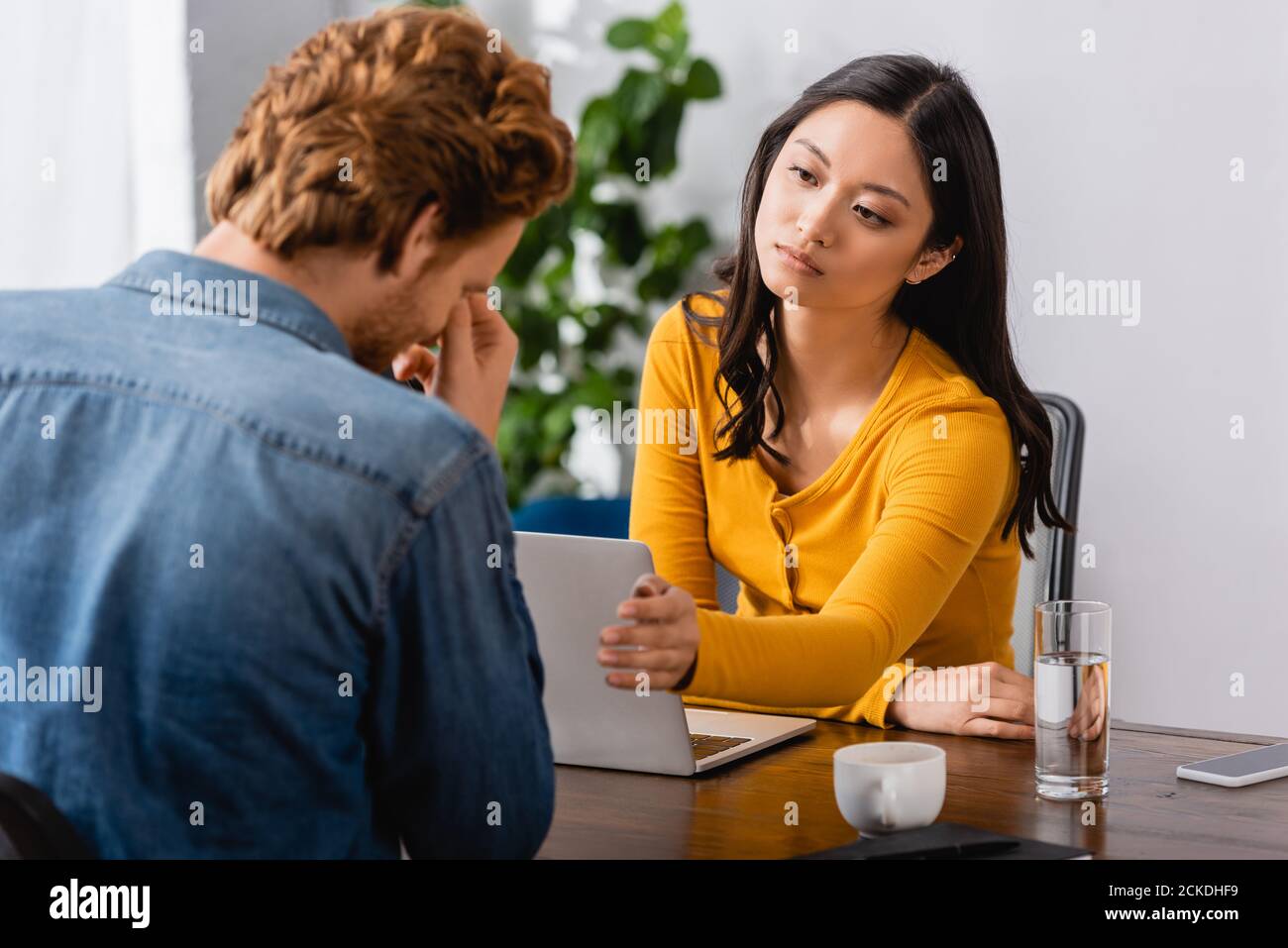 young asian broadcaster outstretching hand near confused man touching ...