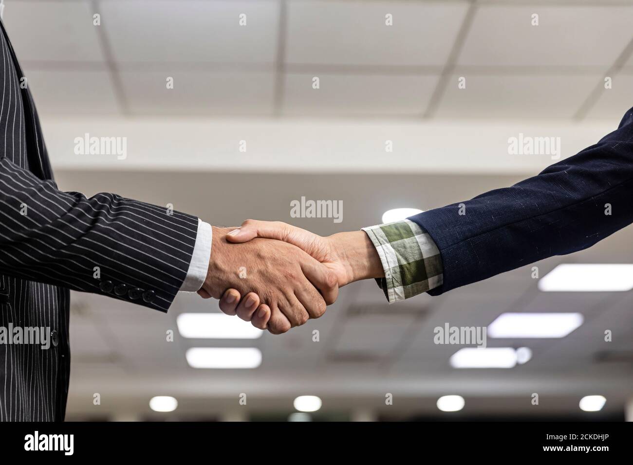 Close up pic of two young Asian men shaking hands, greeting with client ...