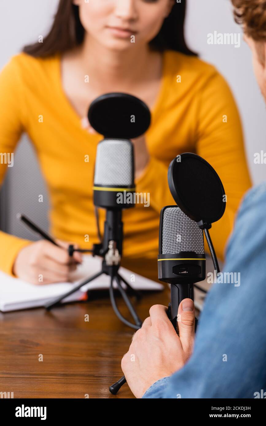 cropped view of broadcaster writing in notebook during interview with ...