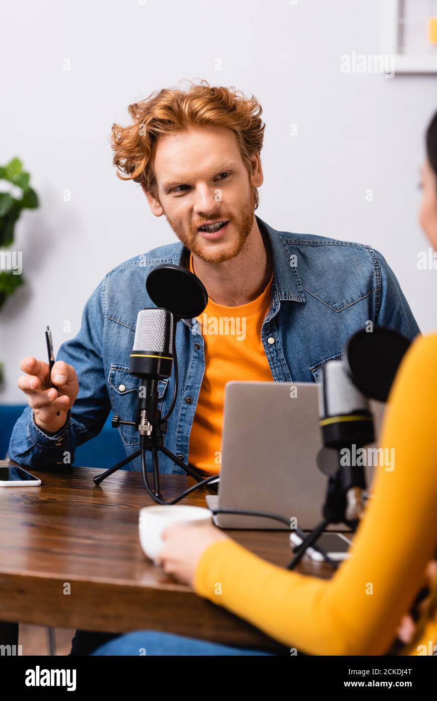 selective focus of woman and redhead interviewer holding pen and ...
