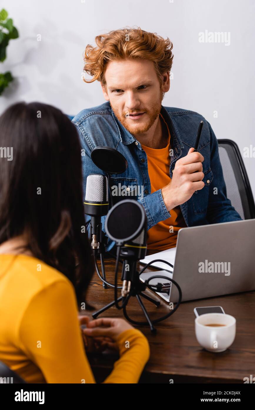 back view of brunette woman near young redhead interviewer in radio ...