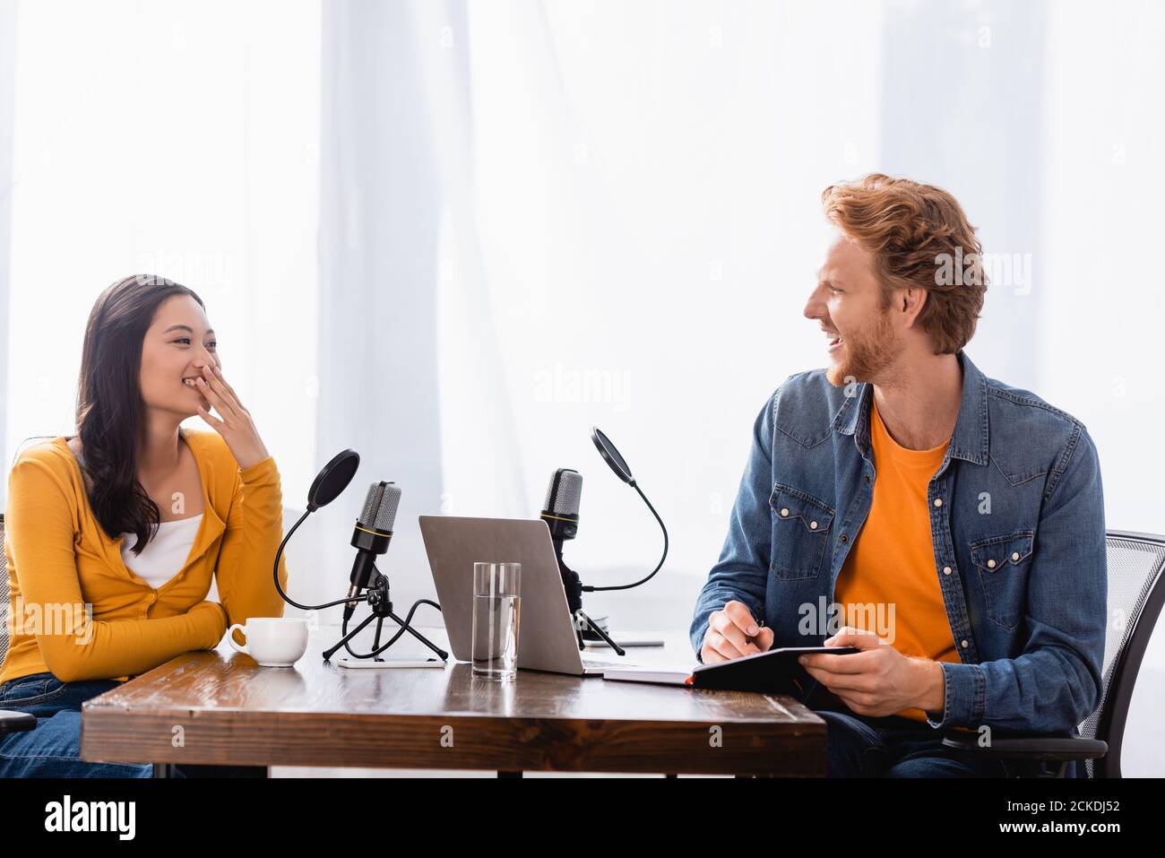 excited asian woman covering mouth with hand during interview with ...
