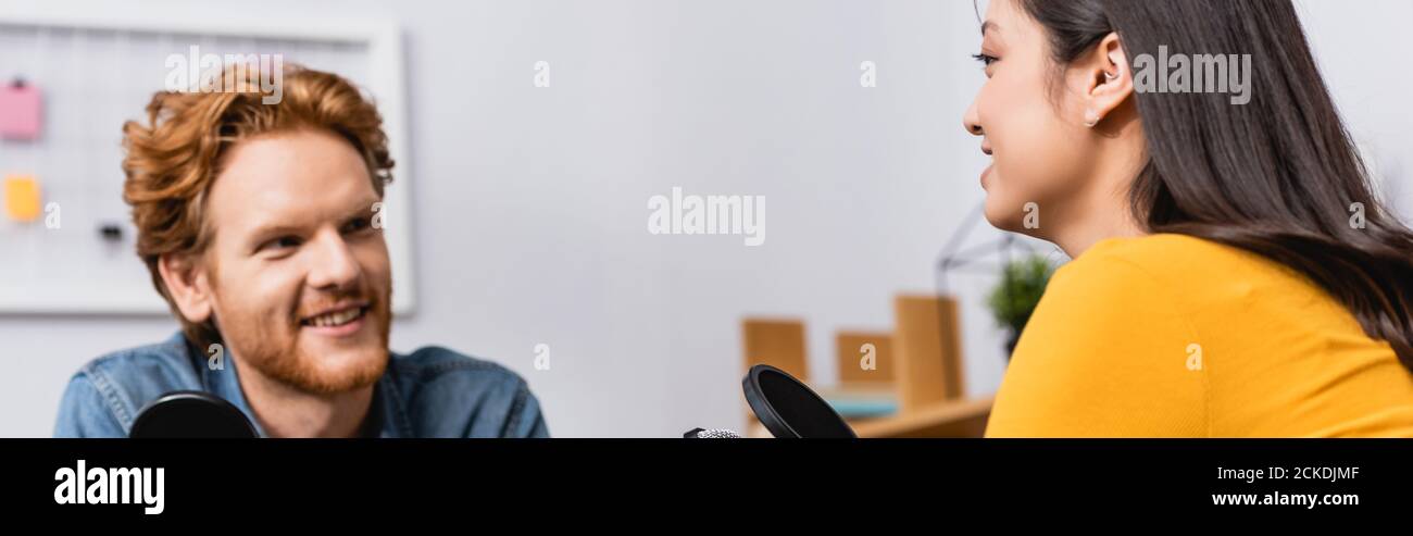 selective focus of young redhead radio host interviewing brunette asian ...