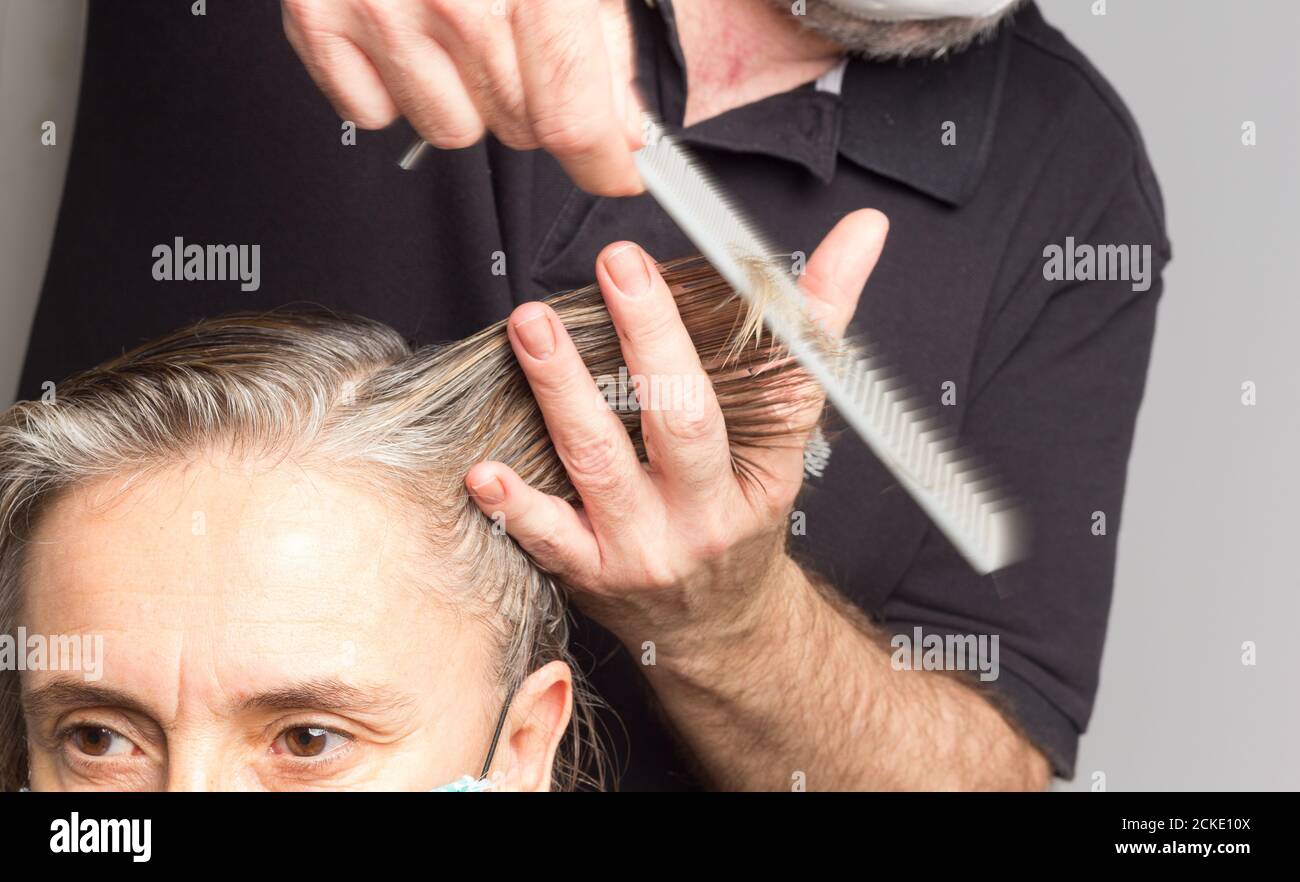 Professional hairdresser cutting a woman's hair with scissors and a ...