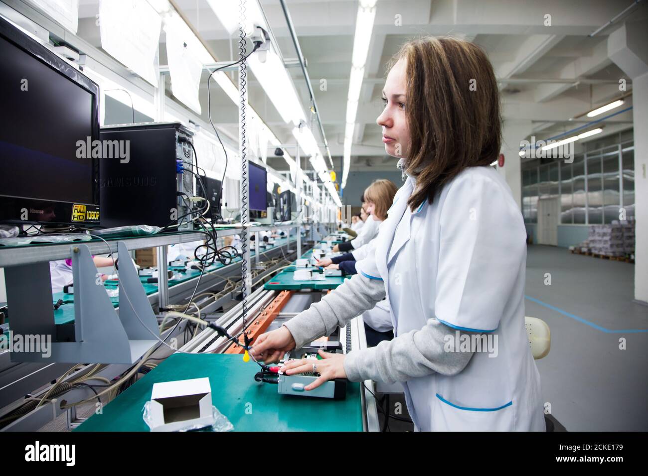 Modern electronic-production plant. Young woman on assembling line ...