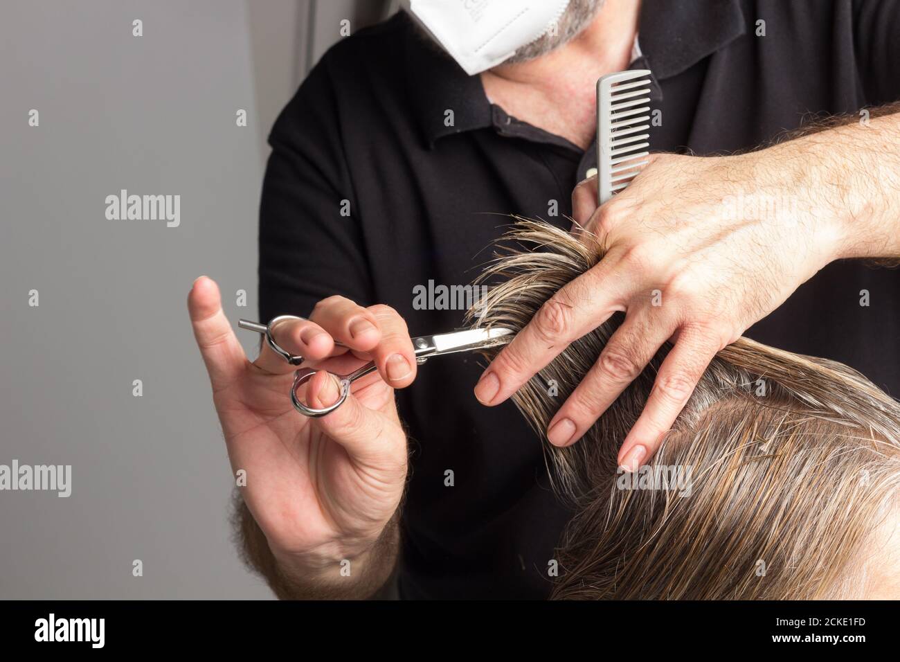 Professional hairdresser cutting a woman's hair with scissors and a ...