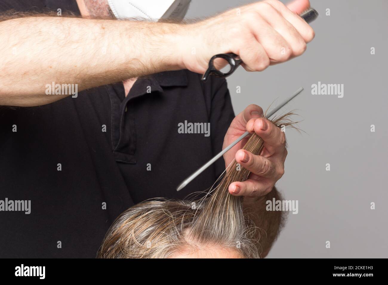 Professional hairdresser cutting a woman's hair with scissors and a ...