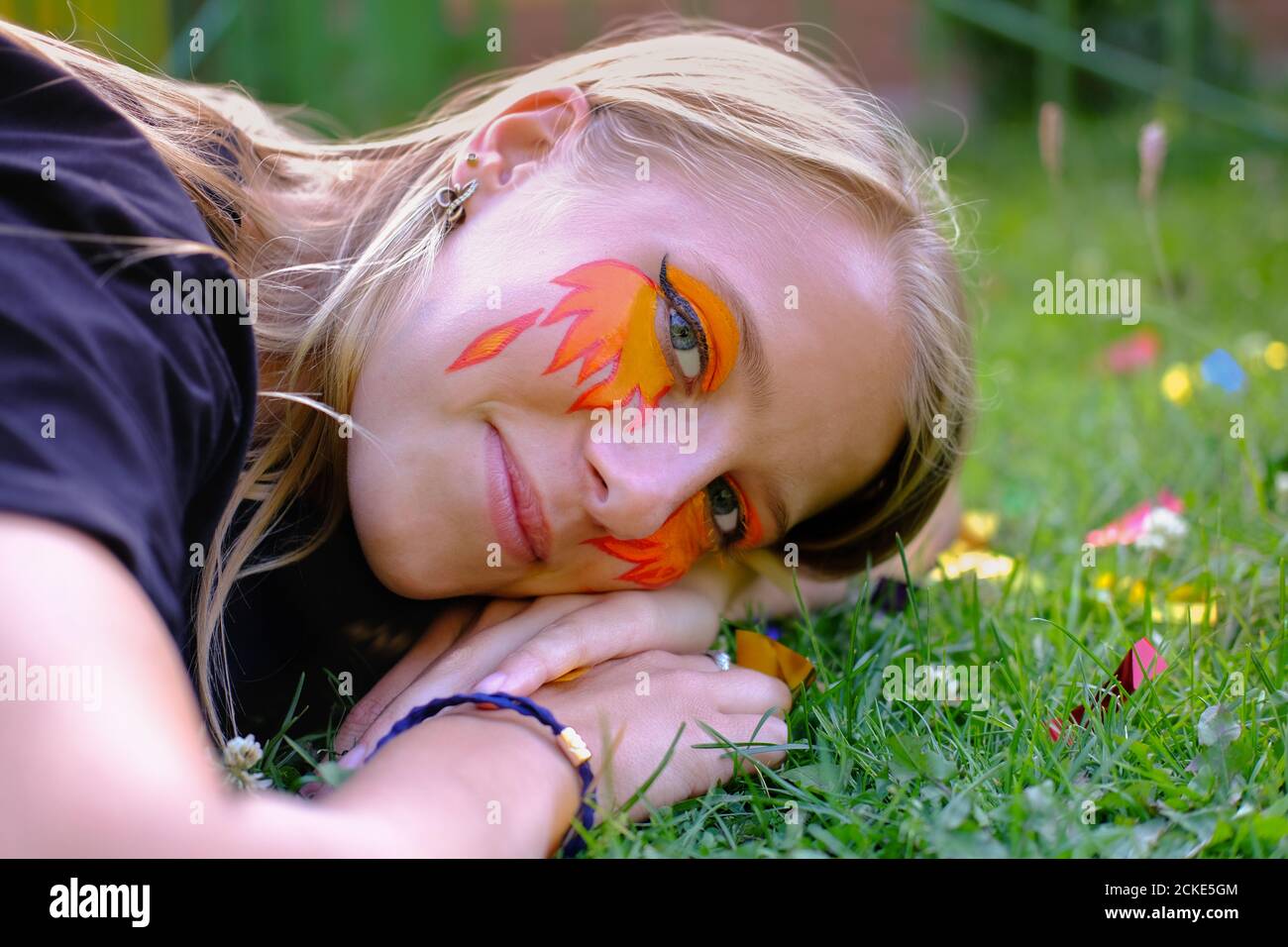 Beautiful teenager girl with face painting lying on a grass. blonde ...