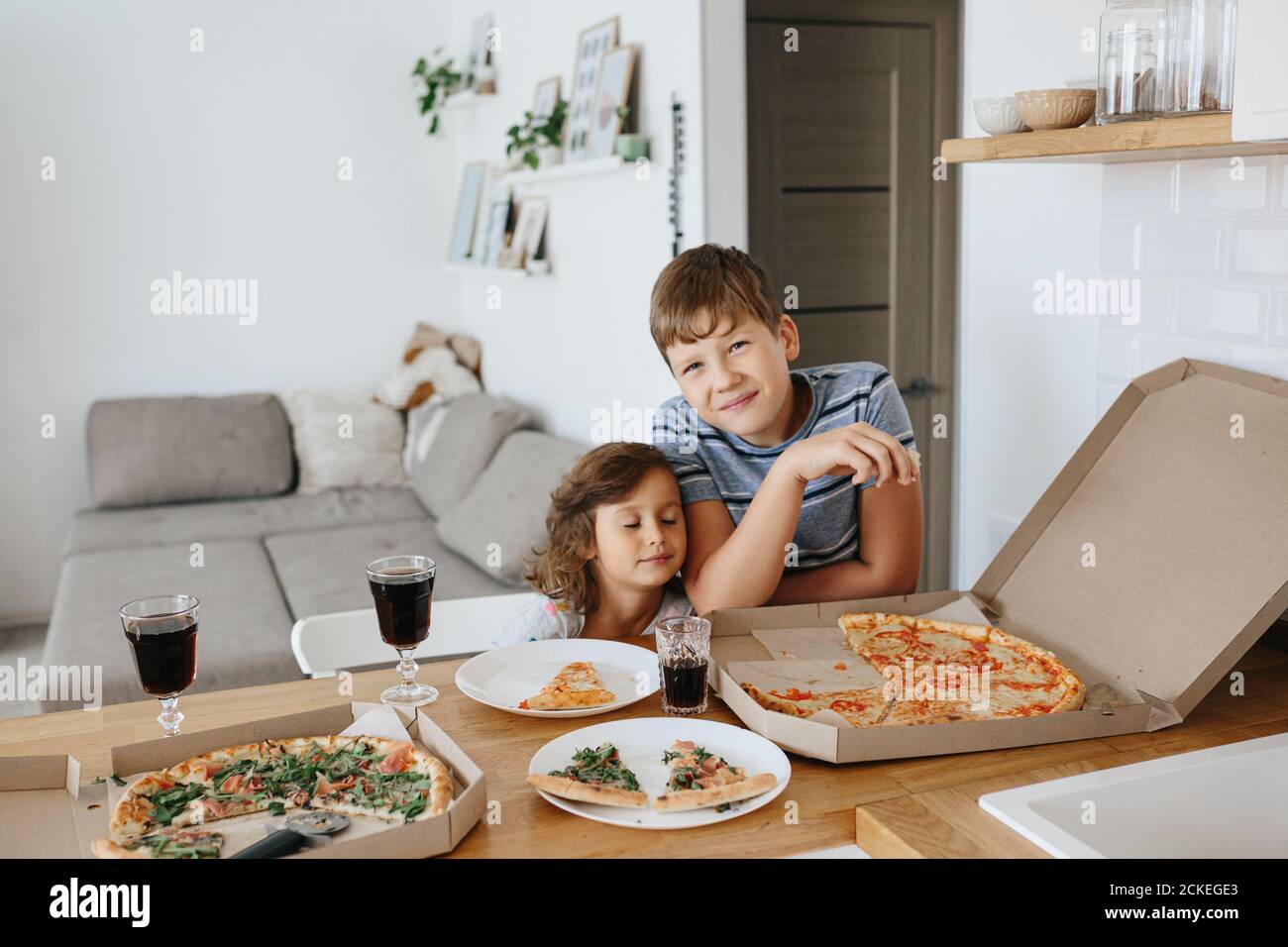 Happy time of eating concept. Kids boy and girl eating pizza at home ...