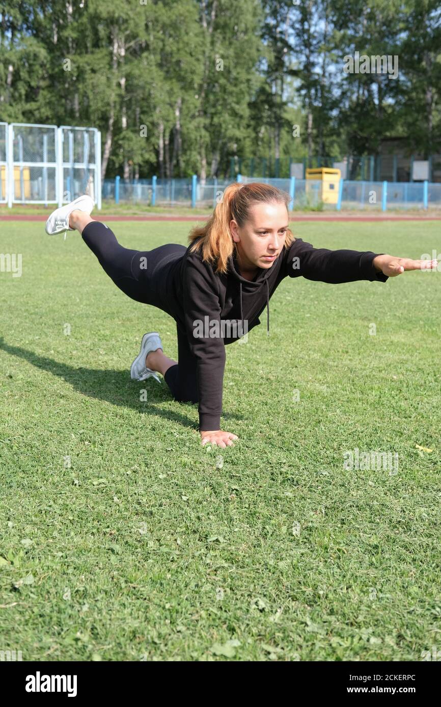beautiful middle age woman doing yoga poses outdoors on a stadium ...