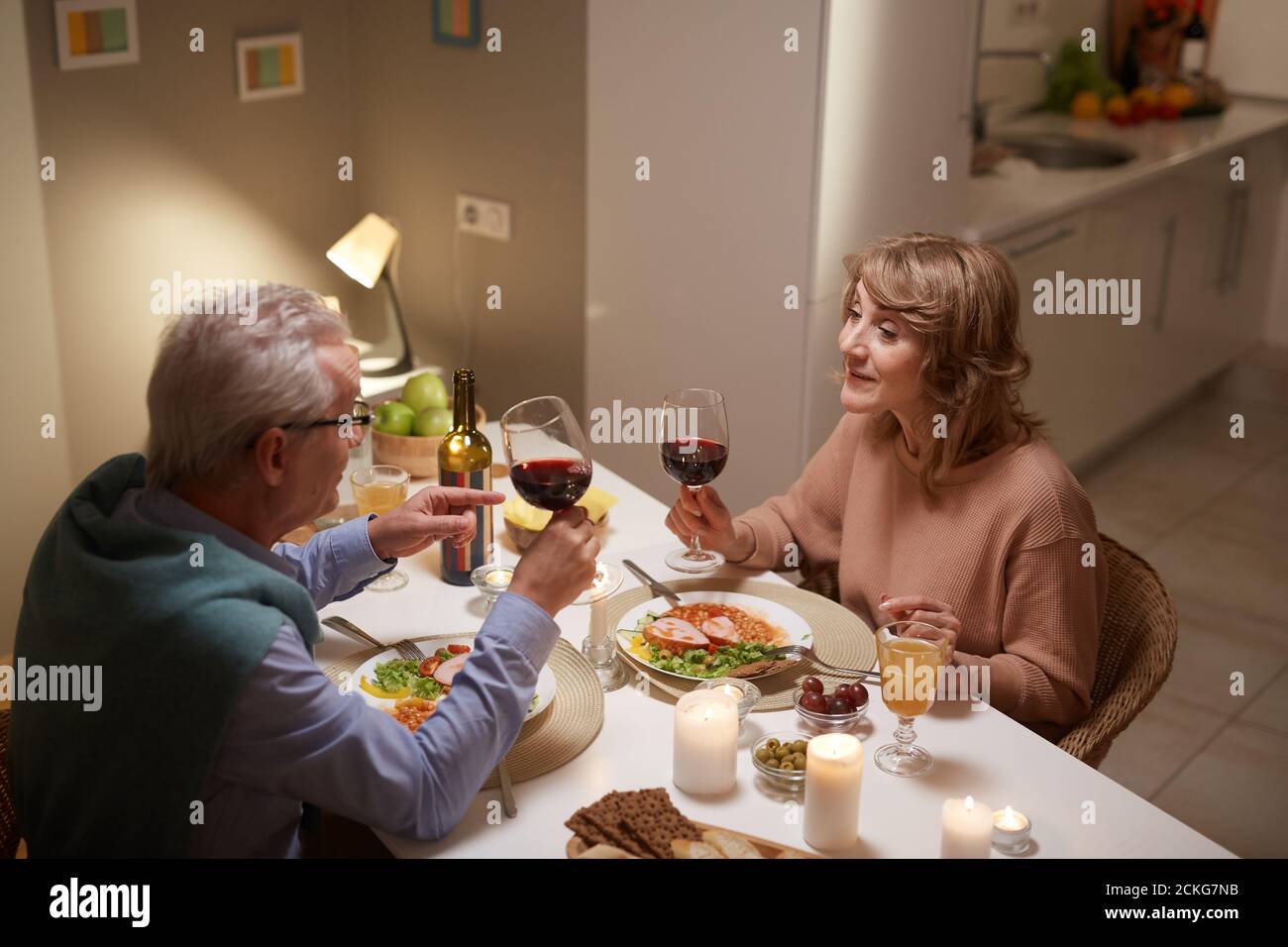 Senior people drinking red wine while sitting at the dining table ...
