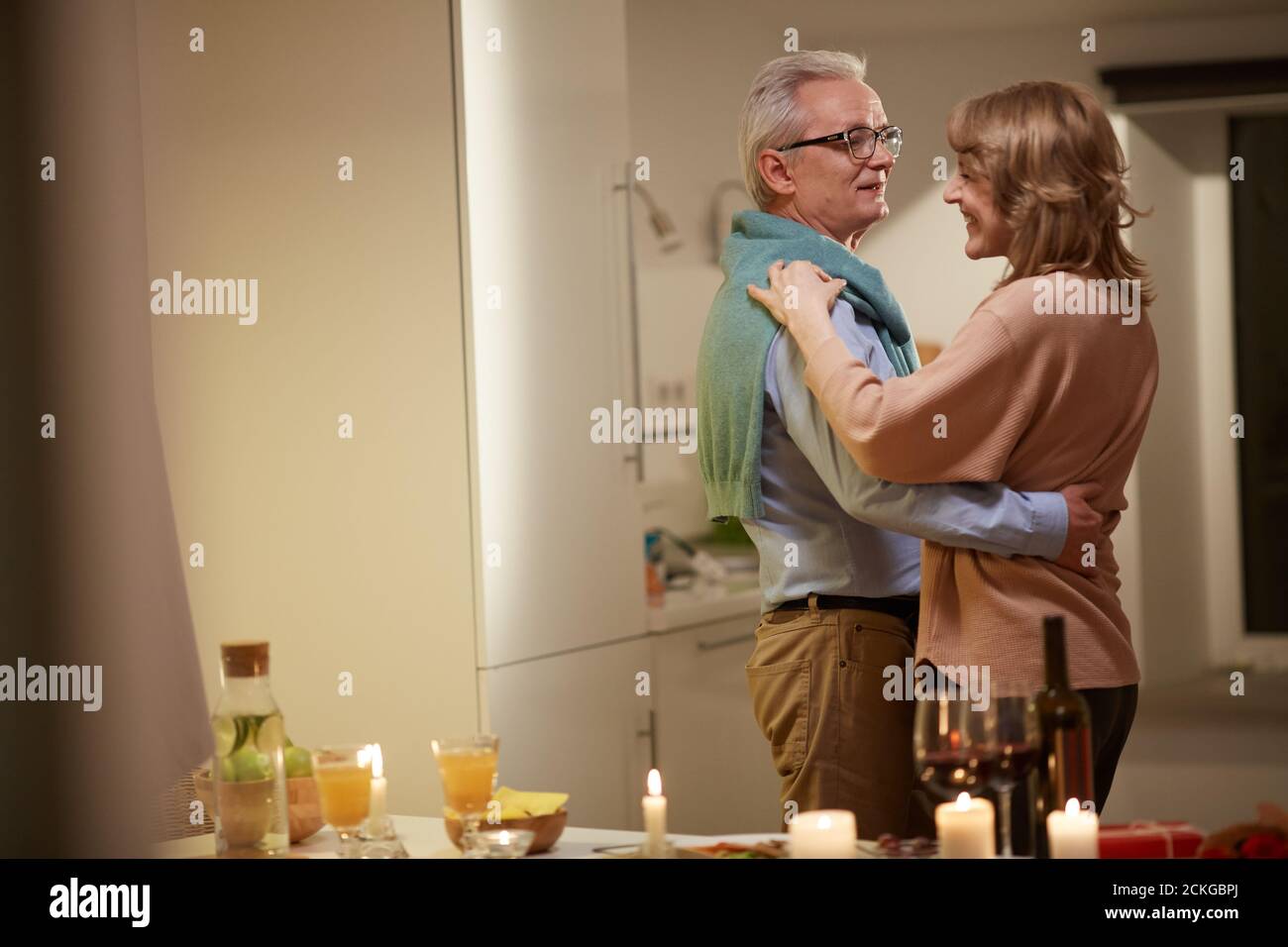 Senior couple embracing each other and dancing during romantic dinner ...