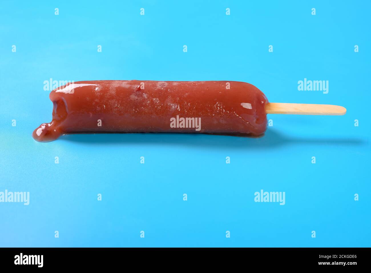 red bean popsicle starts melting on a blue background Stock Photo - Alamy