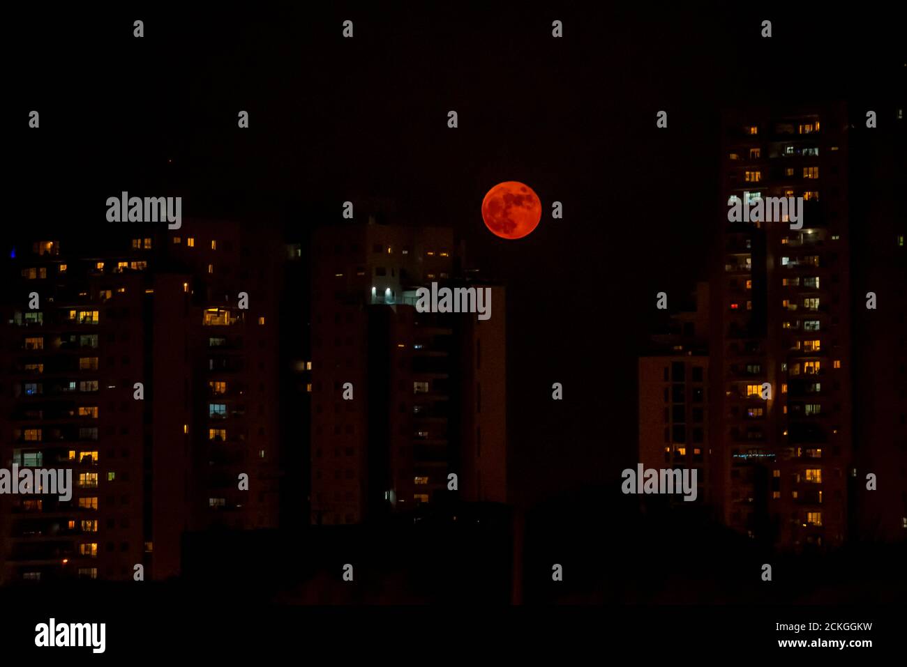 Full orange moon rises over an urban cityscape Stock Photo - Alamy