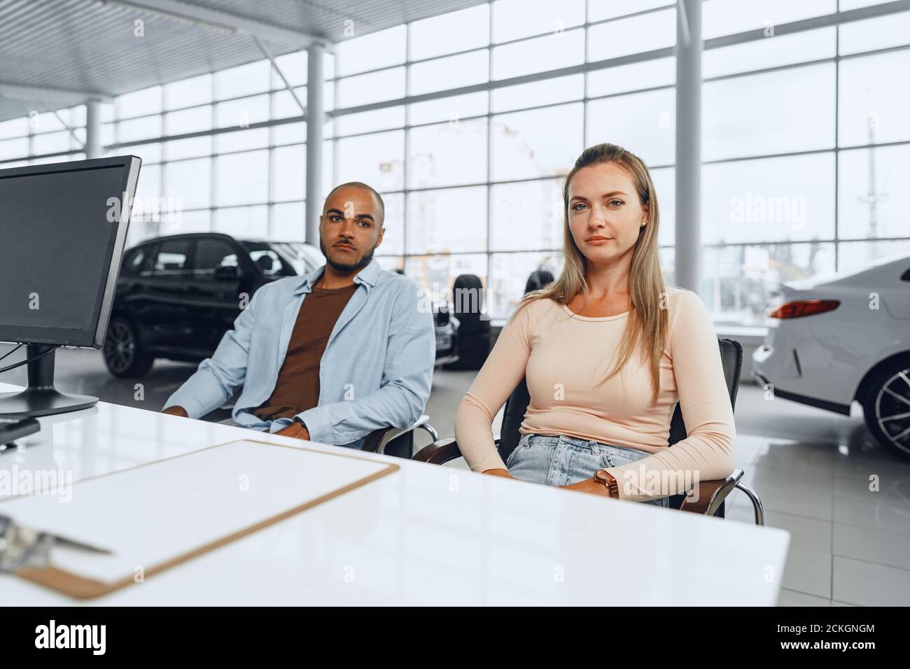 Beautiful young couple signs documents at car dealership showroom Stock ...