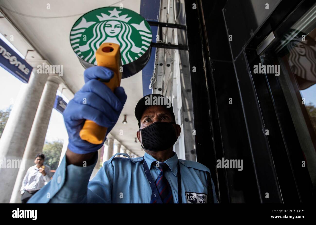 A private security guard checks the body temperature of a customer ...
