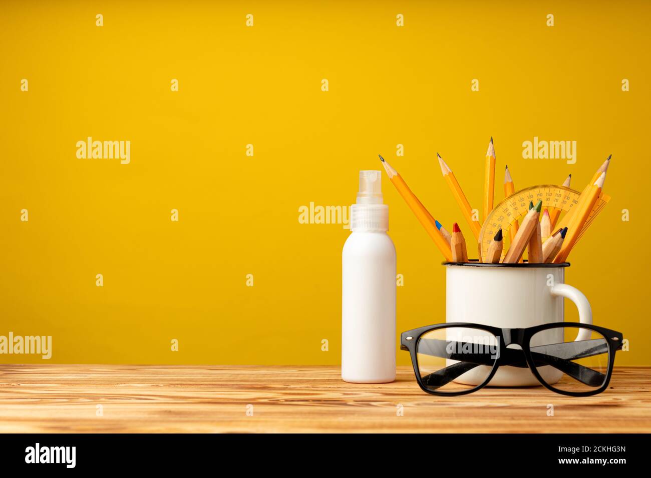 Back to school concept with stationery in cup and hand antiseptic spray ...
