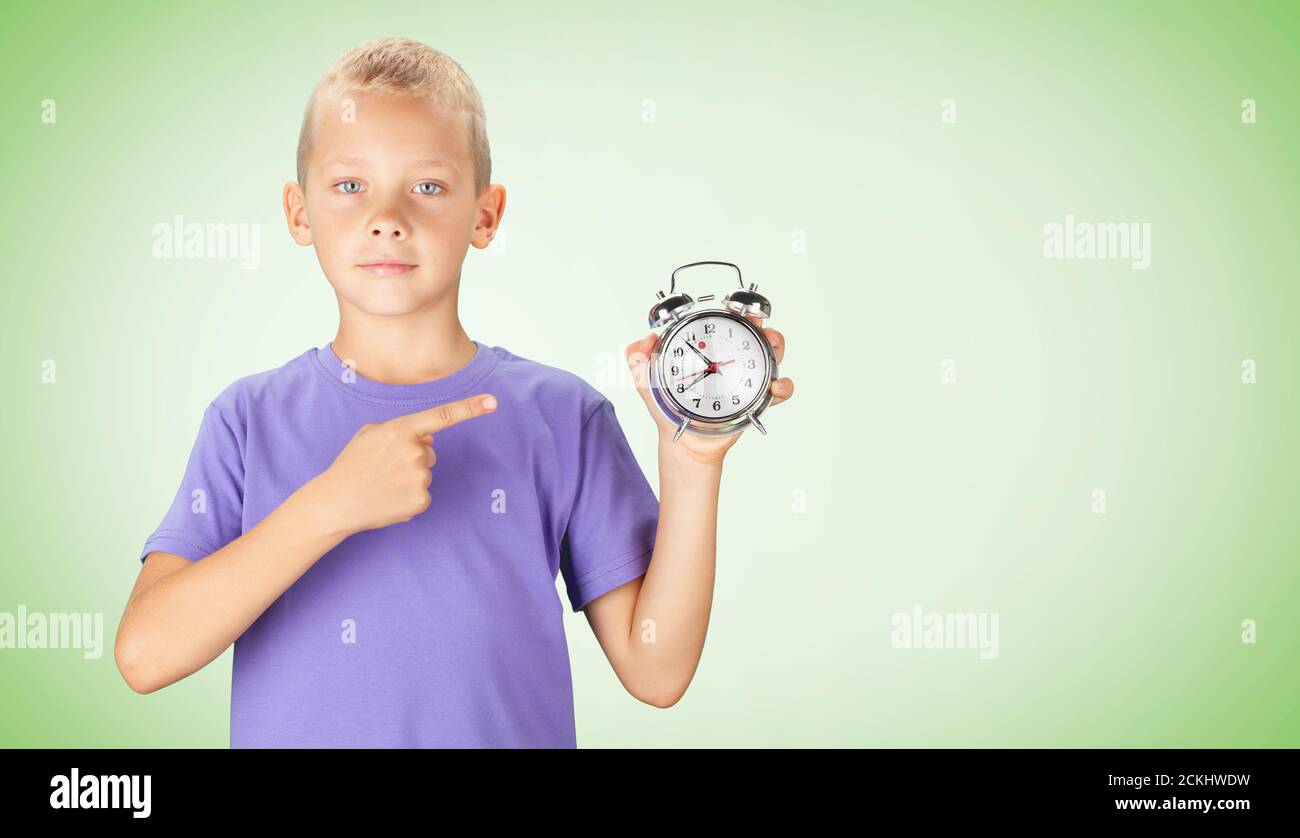 School boy showing alarm clock. Over color background Stock Photo - Alamy