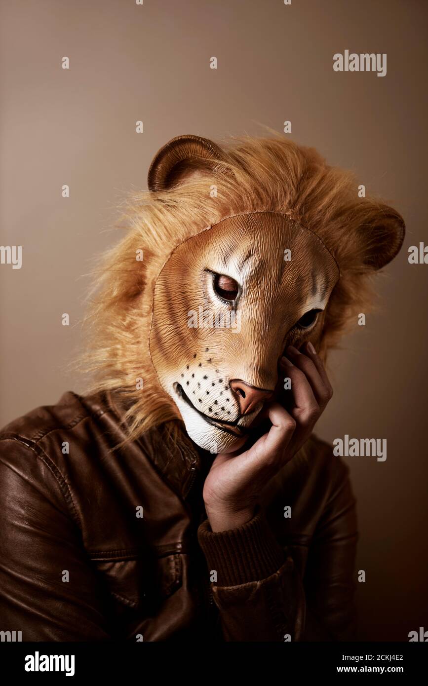 portrait of a man wearing a lion mask supporting his head in his hand ...