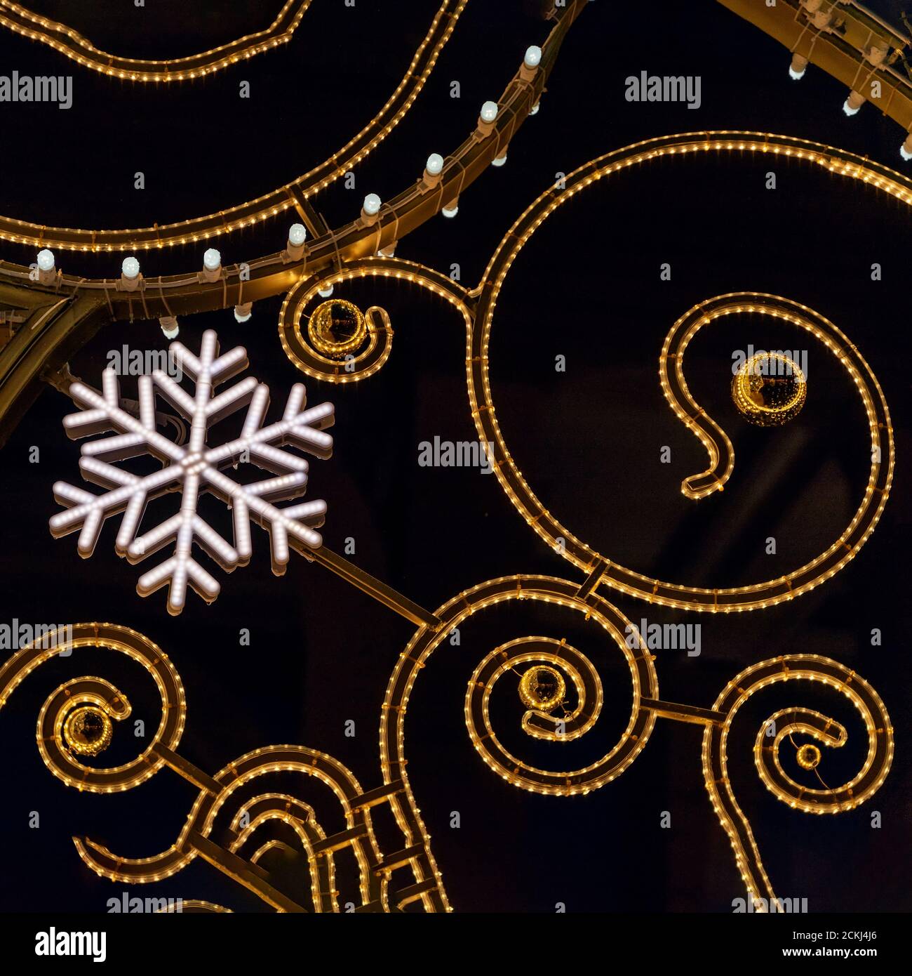 Metallic white golden bright illuminated snowflake, silhouette on night ...